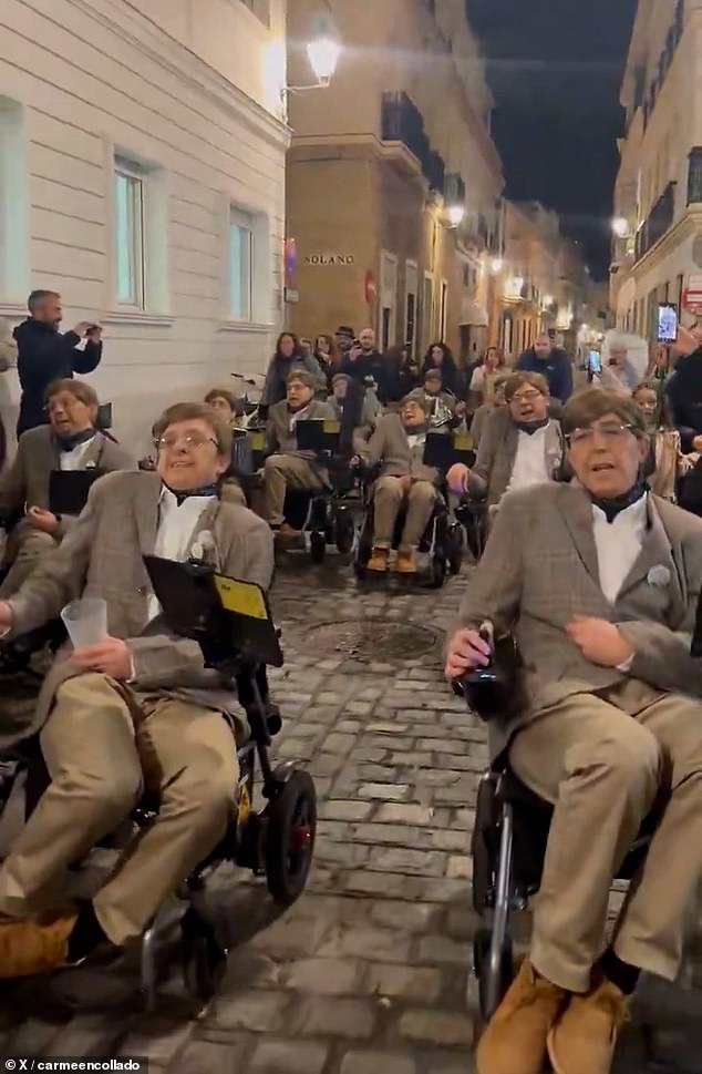 Performers dressed as Stephen Hawking parade and sing in his robotic ...