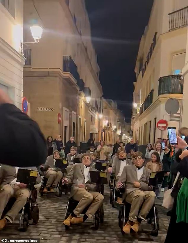 Performers dressed as Stephen Hawking parade and sing in his robotic ...