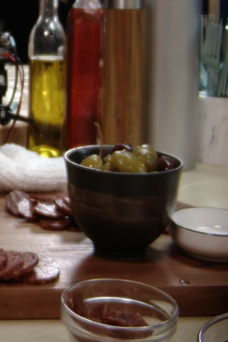 Elegante tabla de aceitunas y quesos con hierbas frescas