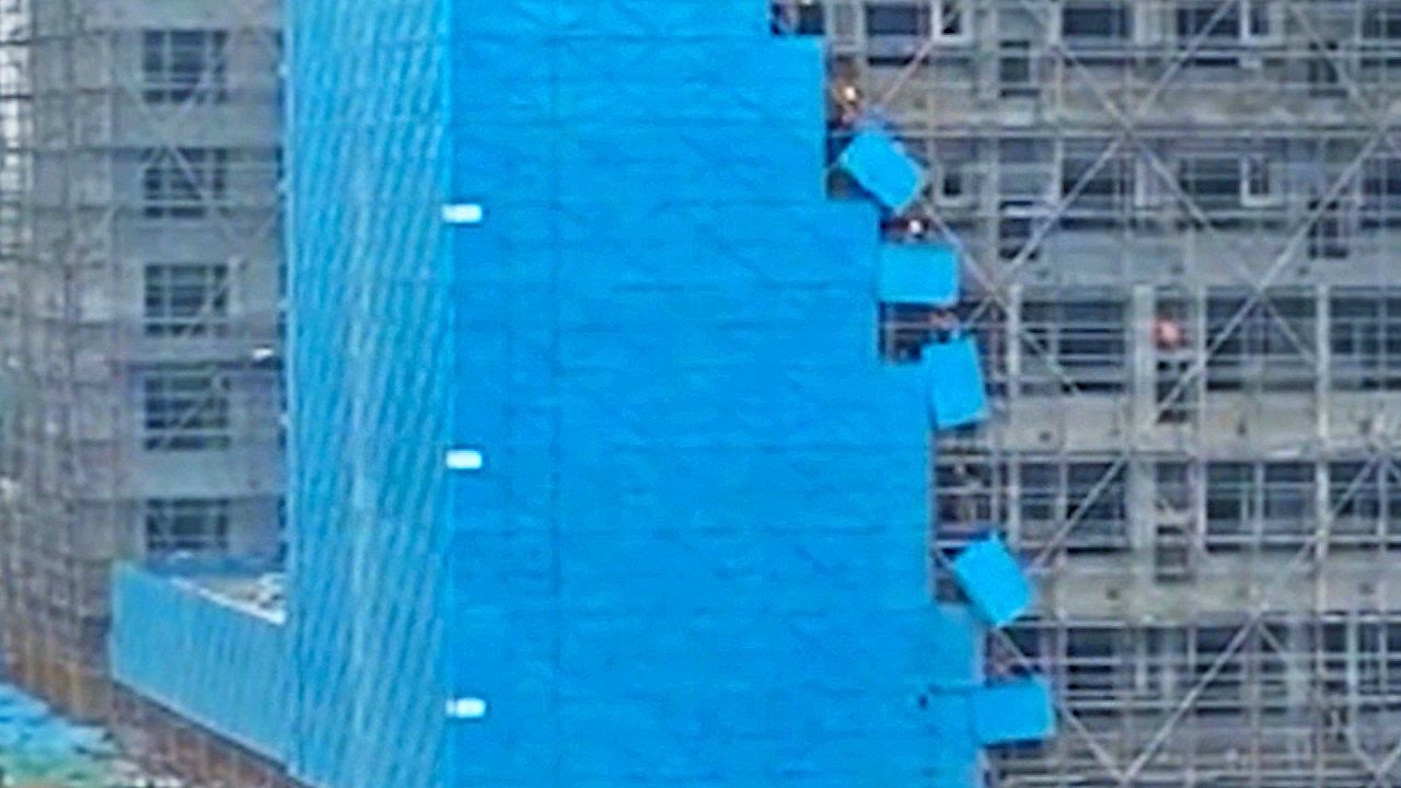 Construction workers move steel panels like a line of ants