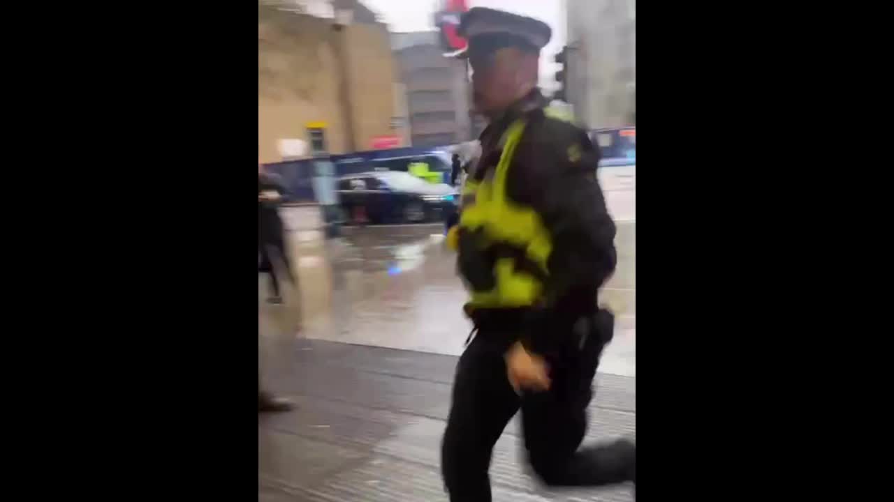 Police officer stumbles on wet ground during station rush in London, UK