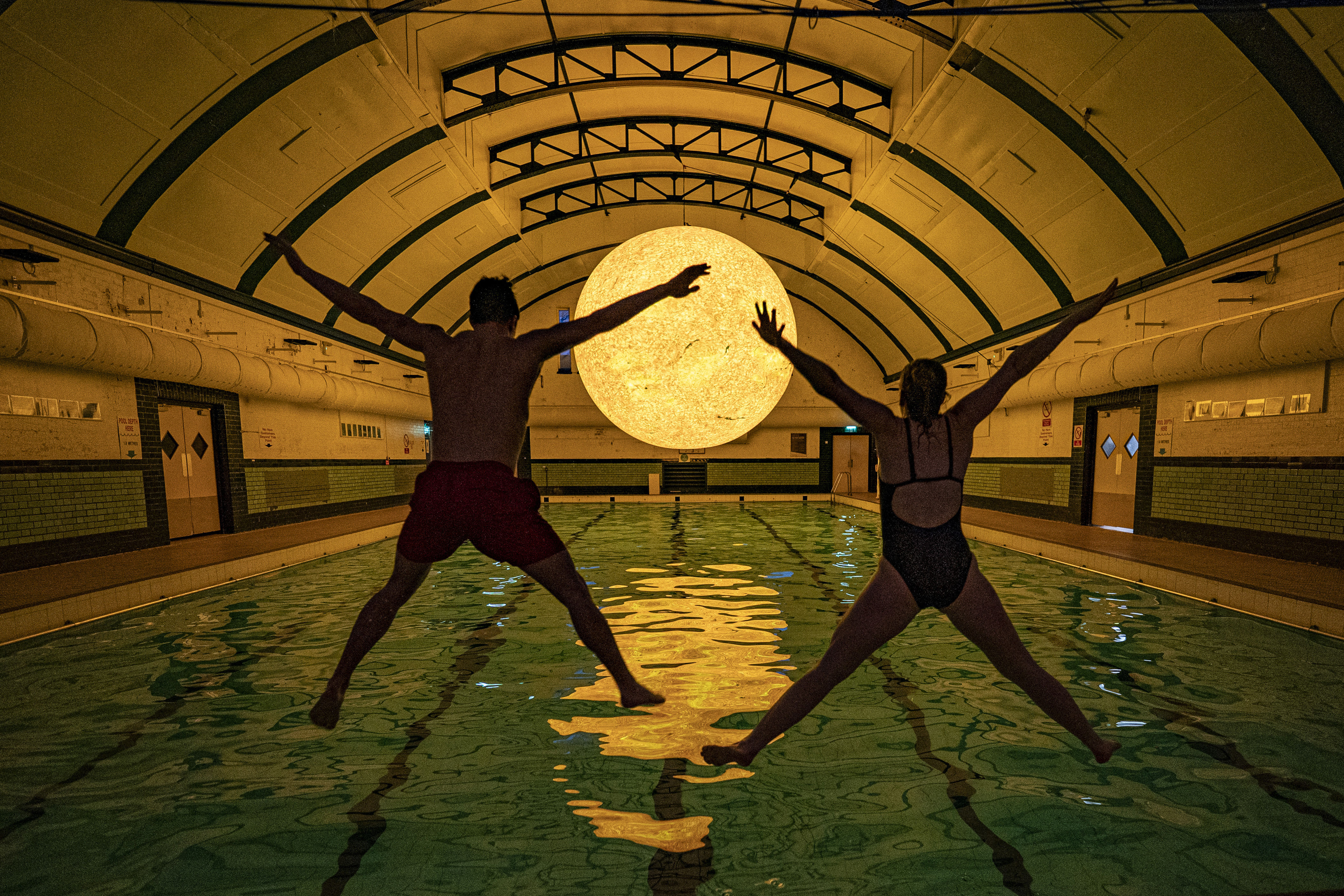Sun artwork suspended above water at community swimming pool