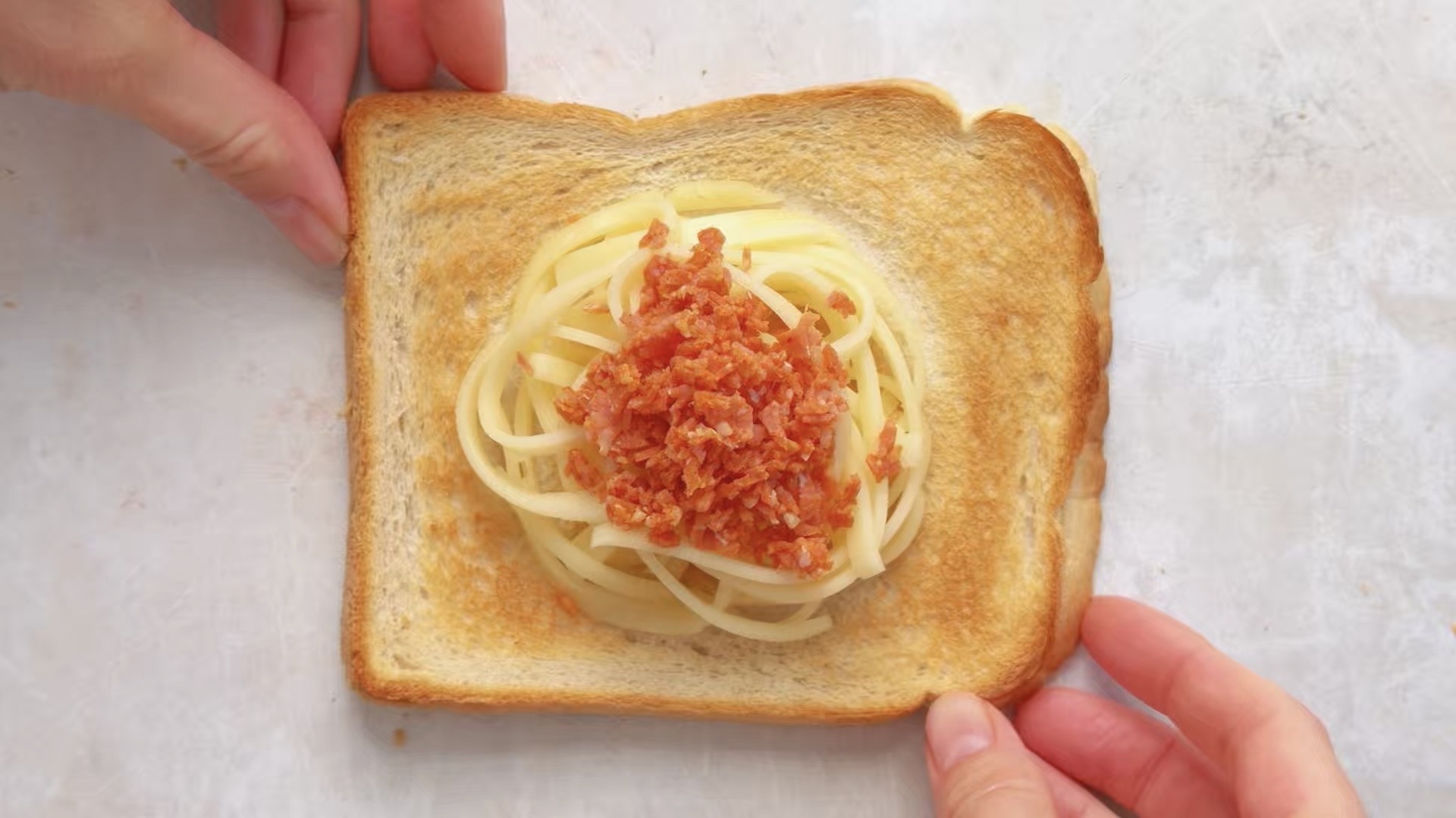 Espaguetis con queso sobre pan tostado