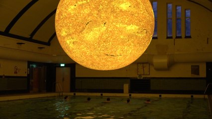 Sun artwork suspended above water at community swimming pool