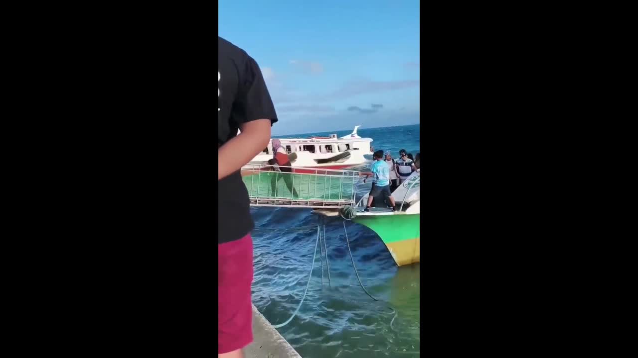 Passengers struggle to disembark ferry bouncing from choppy sea