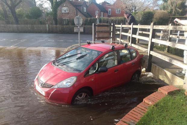 Car swept against footbridge at ford amid flood warnings