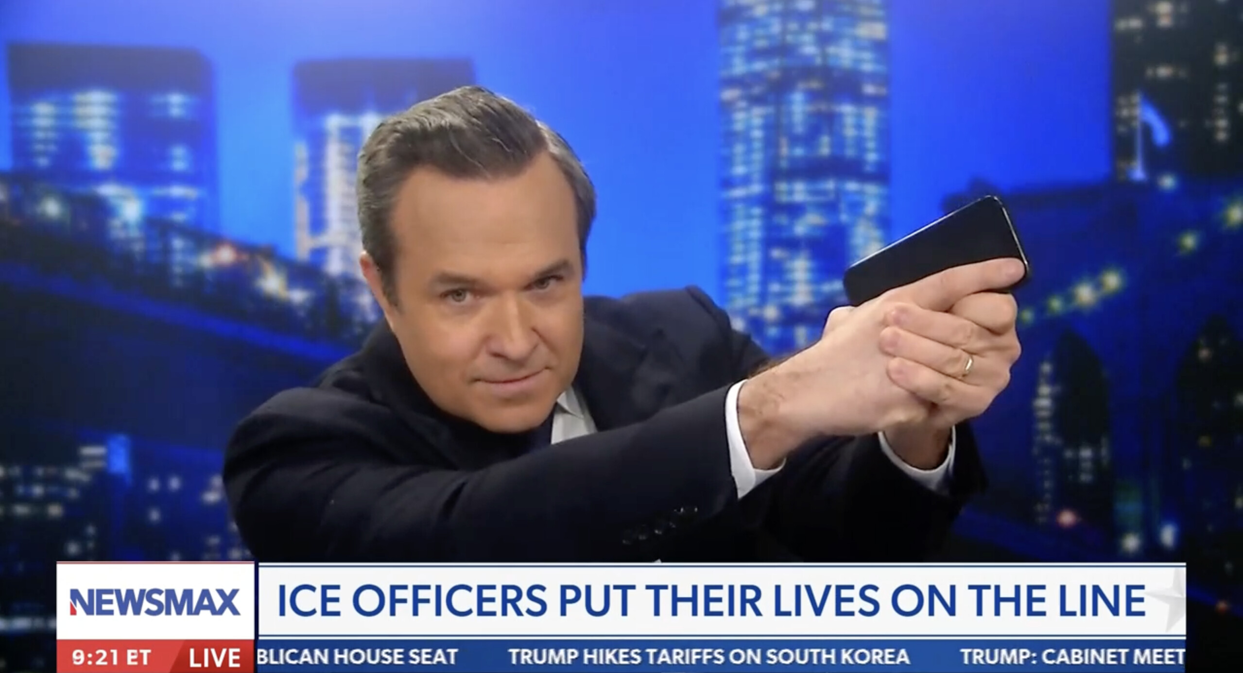 Newsmax host holds his phone like a firearm in defense of ICE agents ...