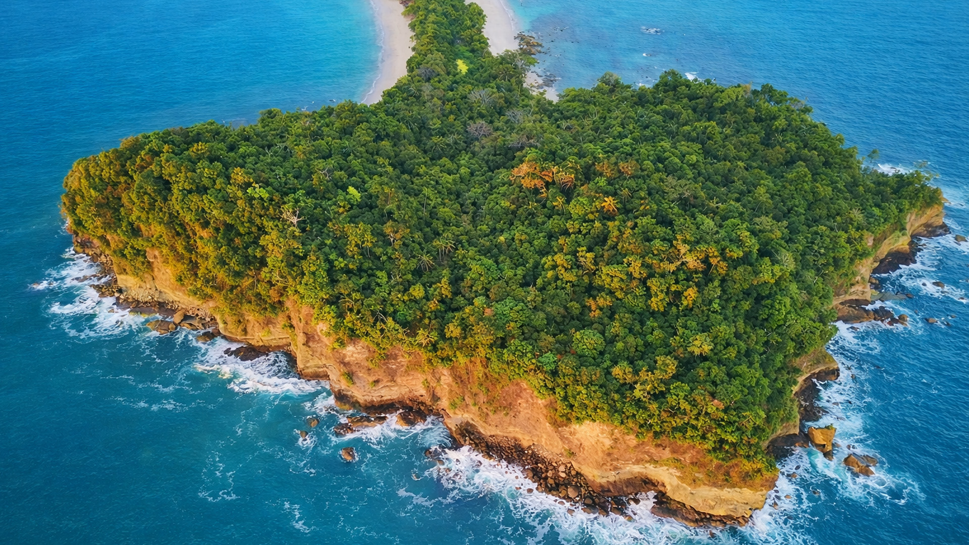 Cliffside forest island rising above the wild tropical ocean