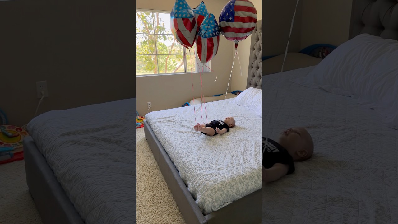 Baby plays with three giant US flag balloons