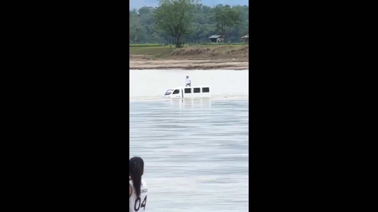 Driver stranded in middle of river rescued by locals using wooden boats