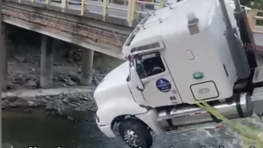 Tractor trailer loses control and ends up hanging off a bridge