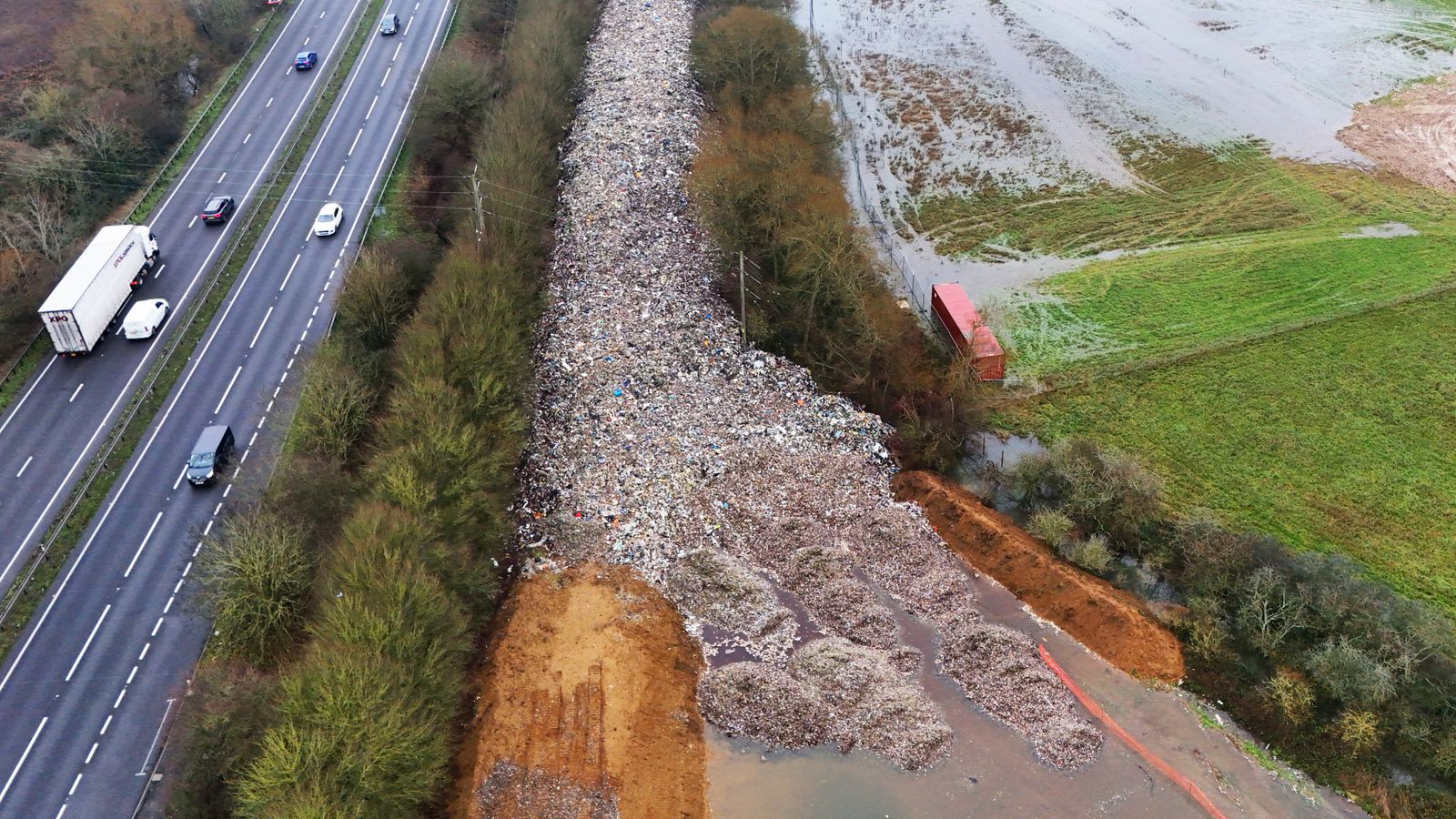 Two men arrested over 60m-long mountain of waste dumped next to river