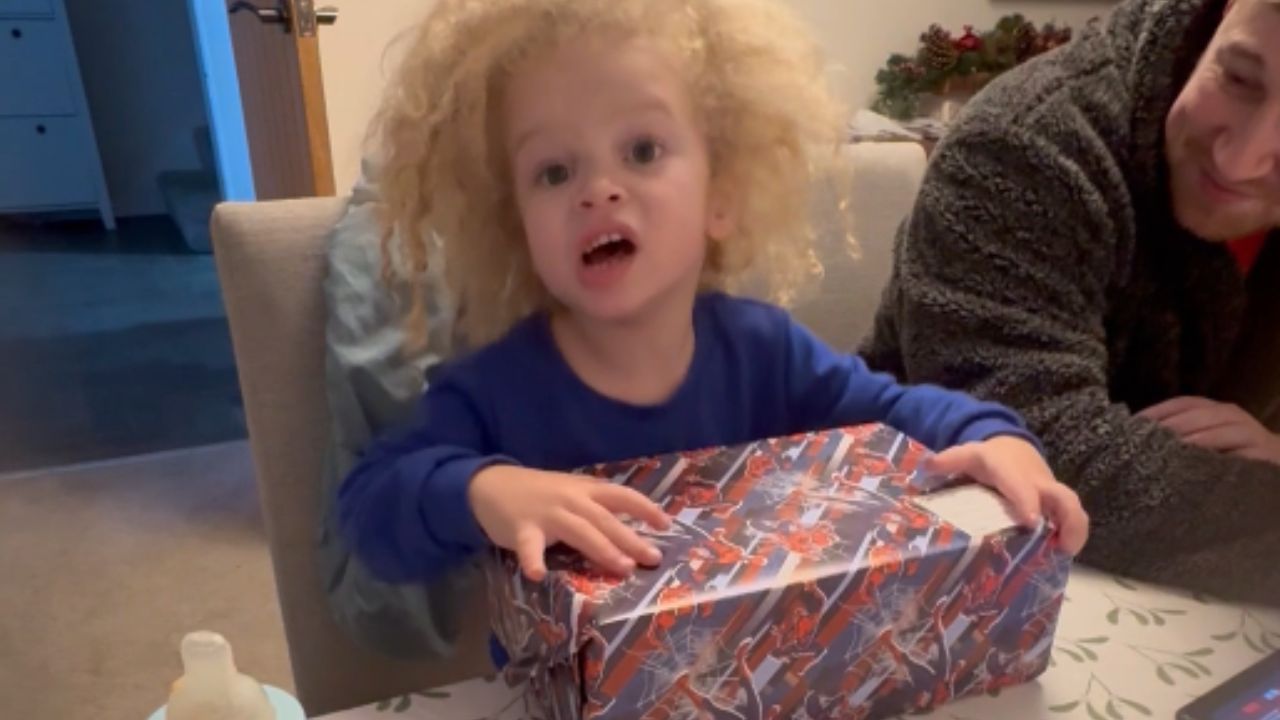 Little boy receives a pair of shoes from grandparents and drops it to ...