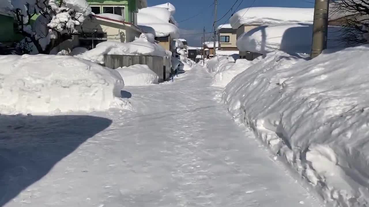 Drivers navigate streets with towering snow walls in Aomori, Japan