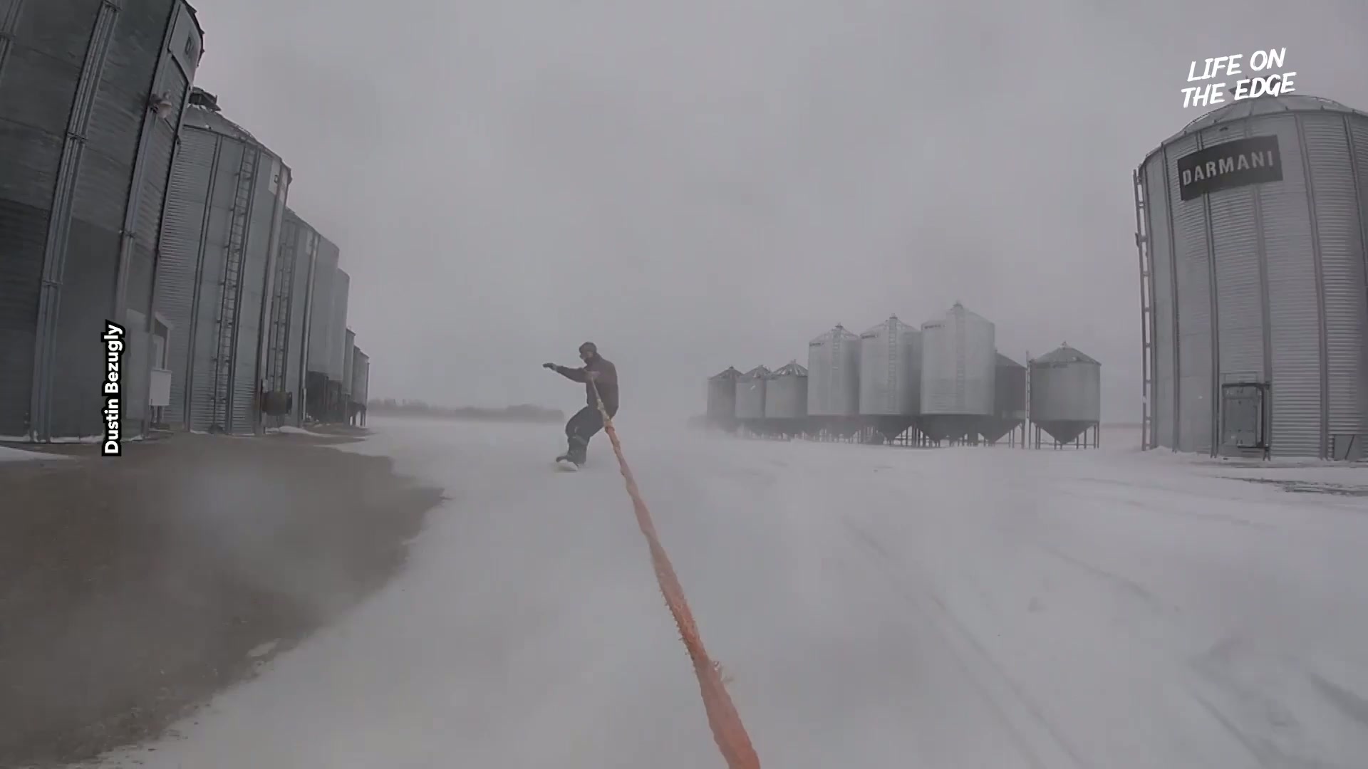 Snowboarder gets pulled along by snowmobile