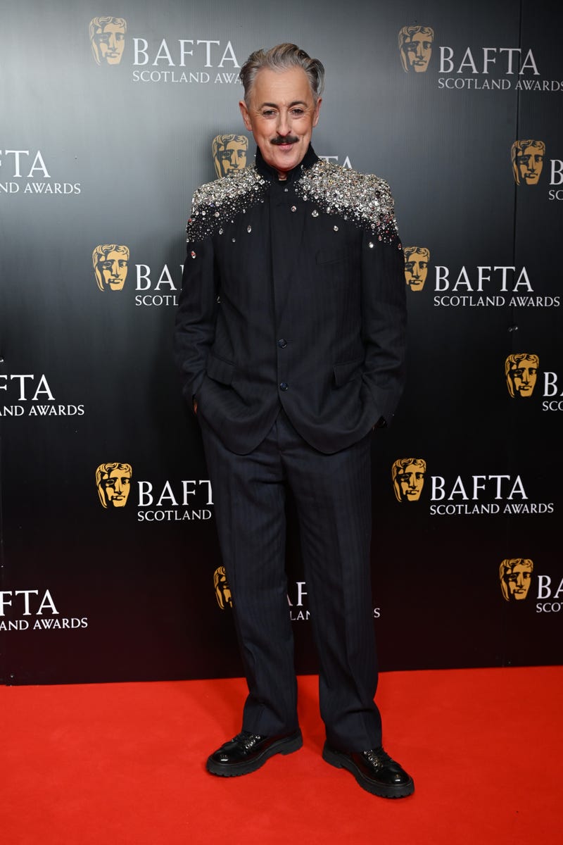 Alan Cumming shines in a sunburst diamond brooch as he arrives to host ...