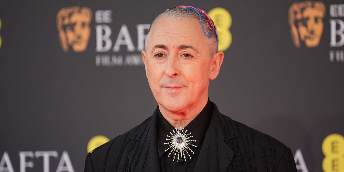 Alan Cumming shines in a sunburst diamond brooch as he arrives to host ...