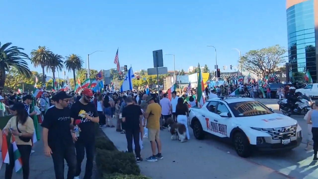 Helicopter flies over flag-waving crowd near Wilshire Boulevard in Los ...