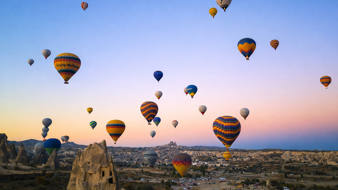Dozens of hot air balloons rise over Cappadocia at sunrise