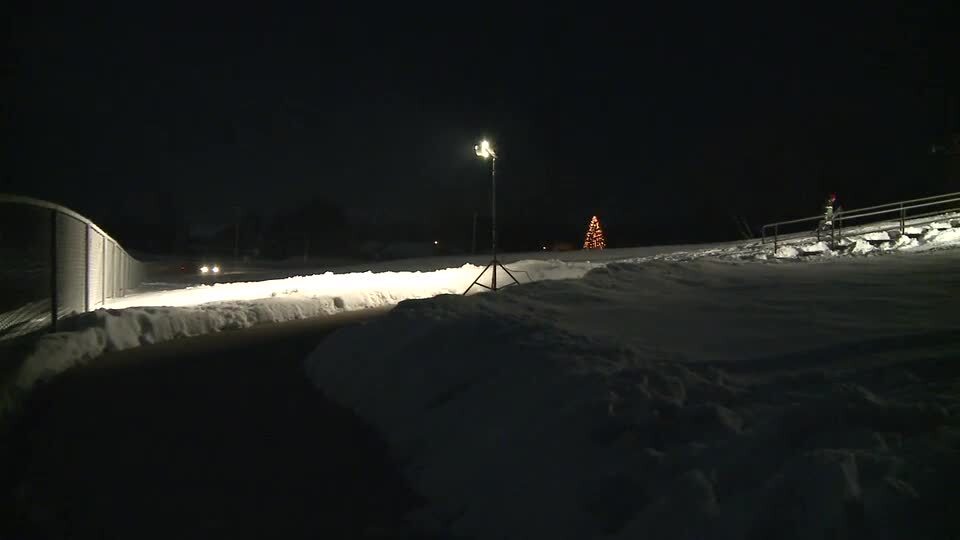 Car does donuts on snowy street at night