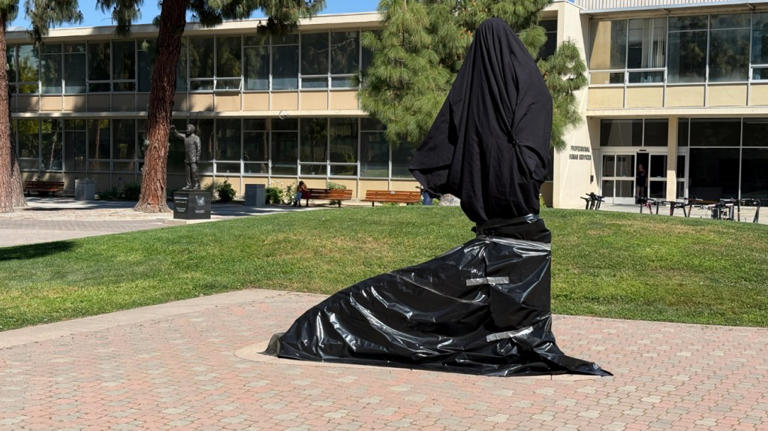 Cesar Chavez statue covered in black tarps and plastic bags at Fresno State