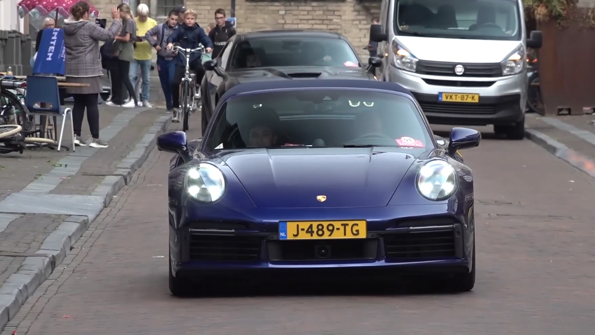 Porsche 911 accelerating through a busy city street