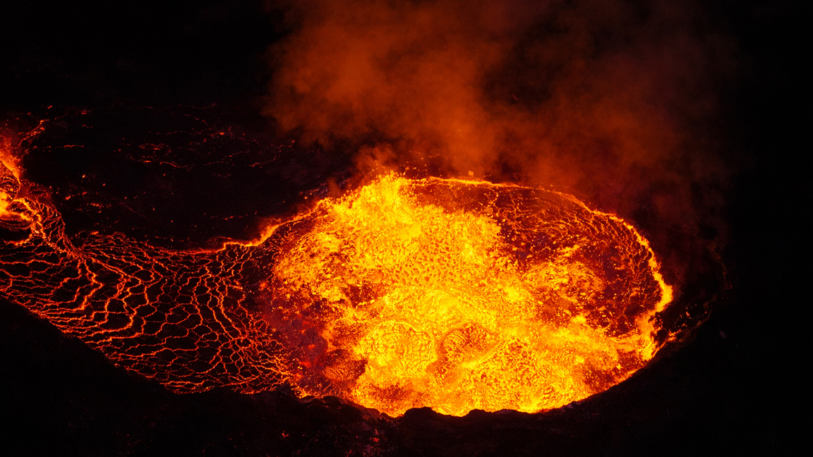 Glowing lava pool boiling at the heart of a volcano