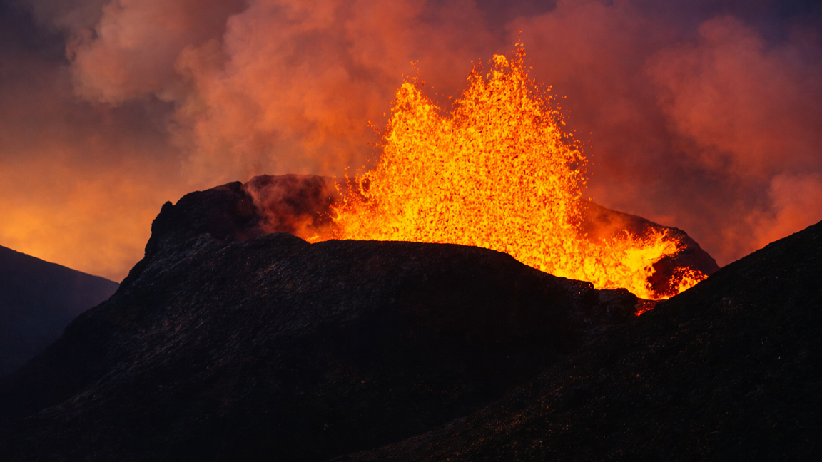 Fiery eruption illuminating the dark volcanic crater