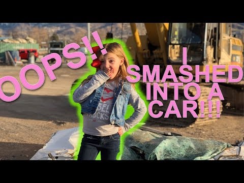 A little girl crashes an excavator into a parked car