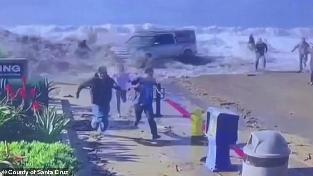 Moment powerful wave crashes over sea wall sweeping away beachgoers