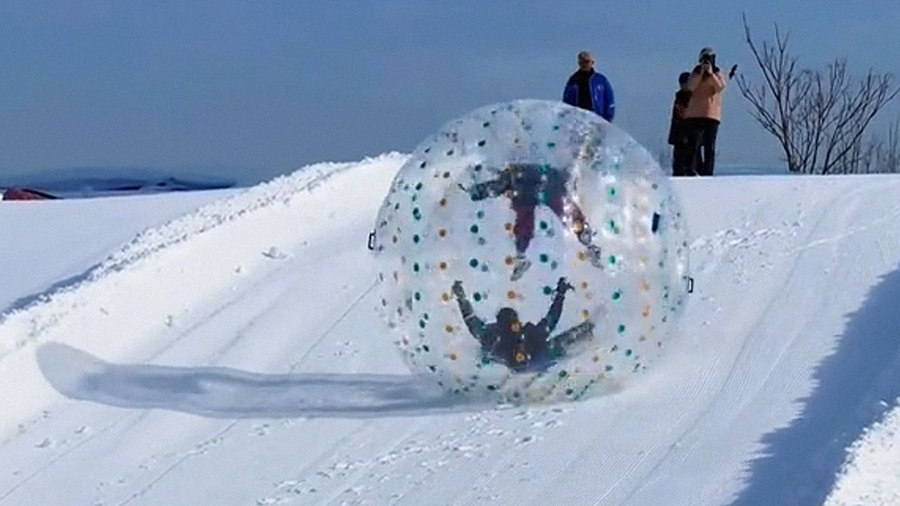 Vacationers roll down snowy hill in giant inflatable hamster balls