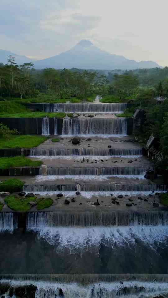 Majestic Terraced Waterfalls with Mountain Backdrop