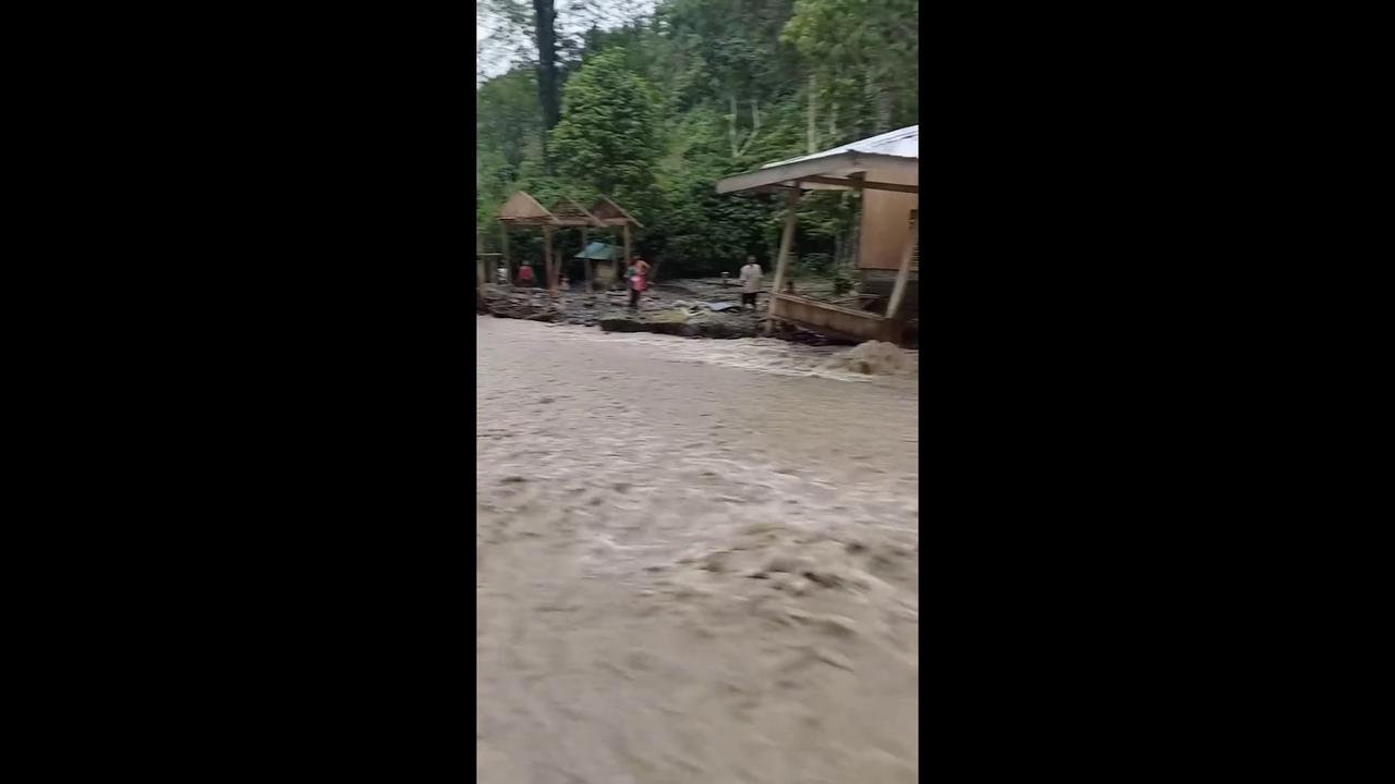Flood surges near riverside homes in the Philippines