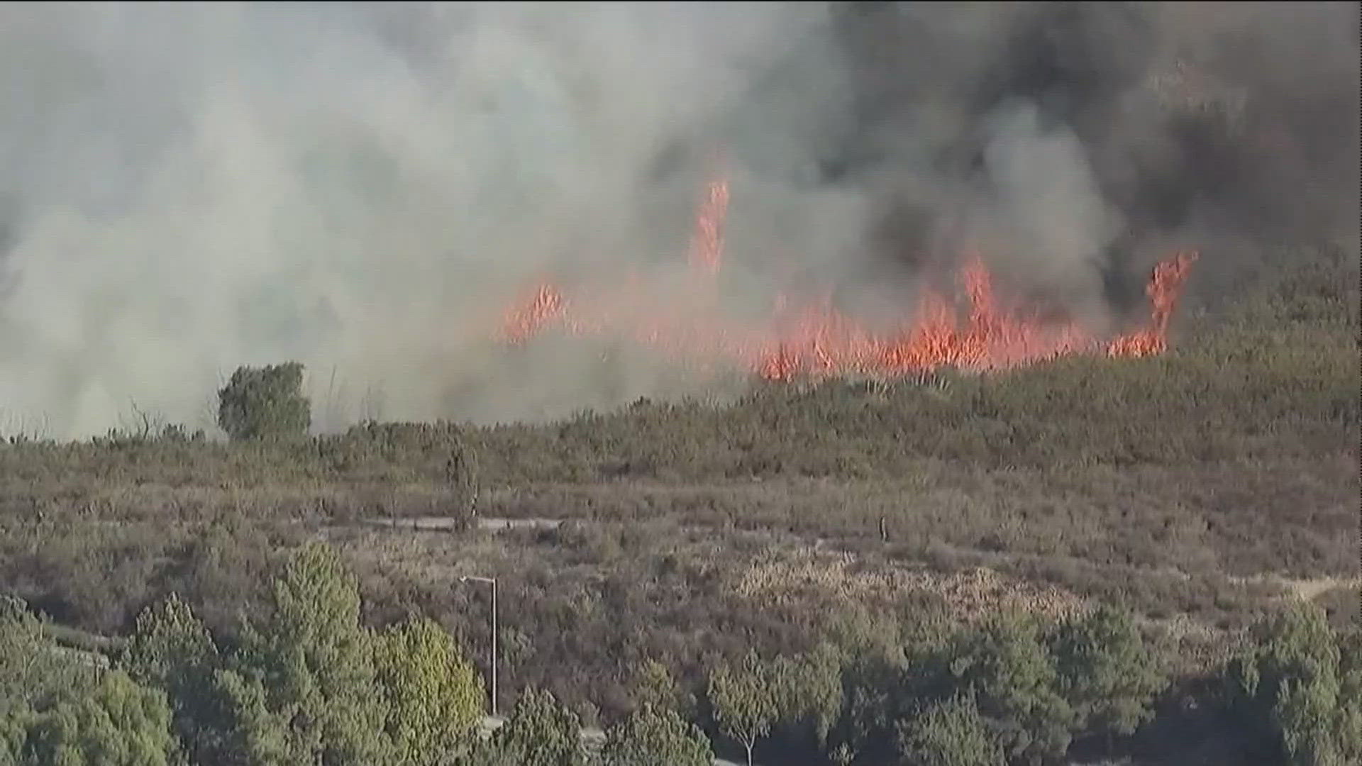 Firefighters try to put out brush fire in Poway during Red Flag Warning