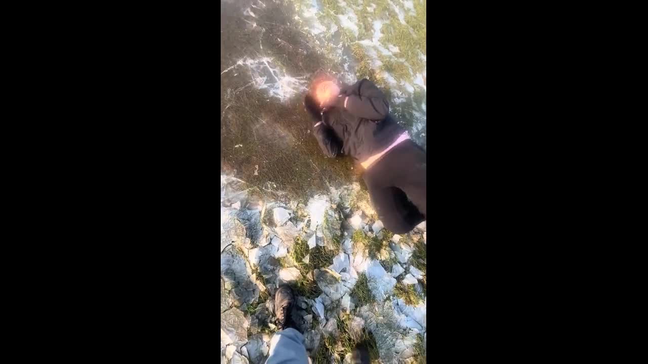 Friends slip while playing on frozen puddle in Hereford, England, UK