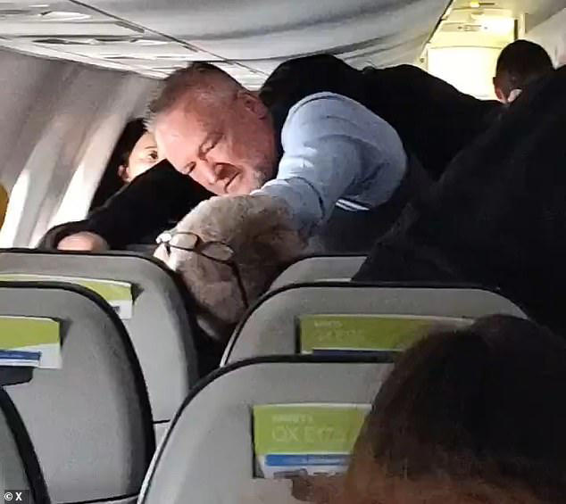 Moment flight attendant restrains passenger pulling woman's hair