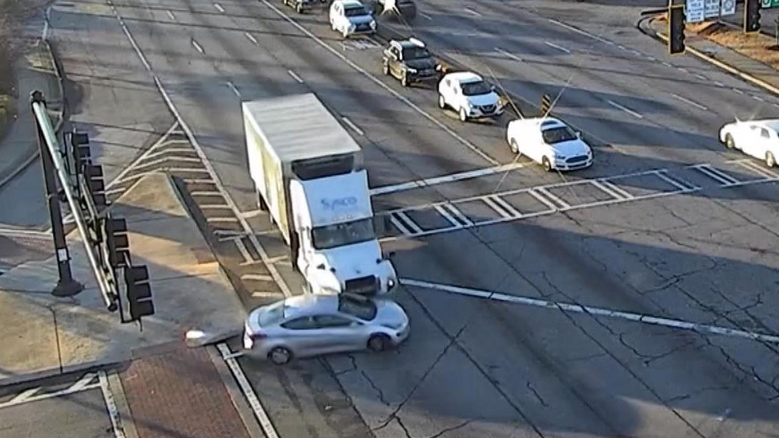 Truck hits car and pushes it along road