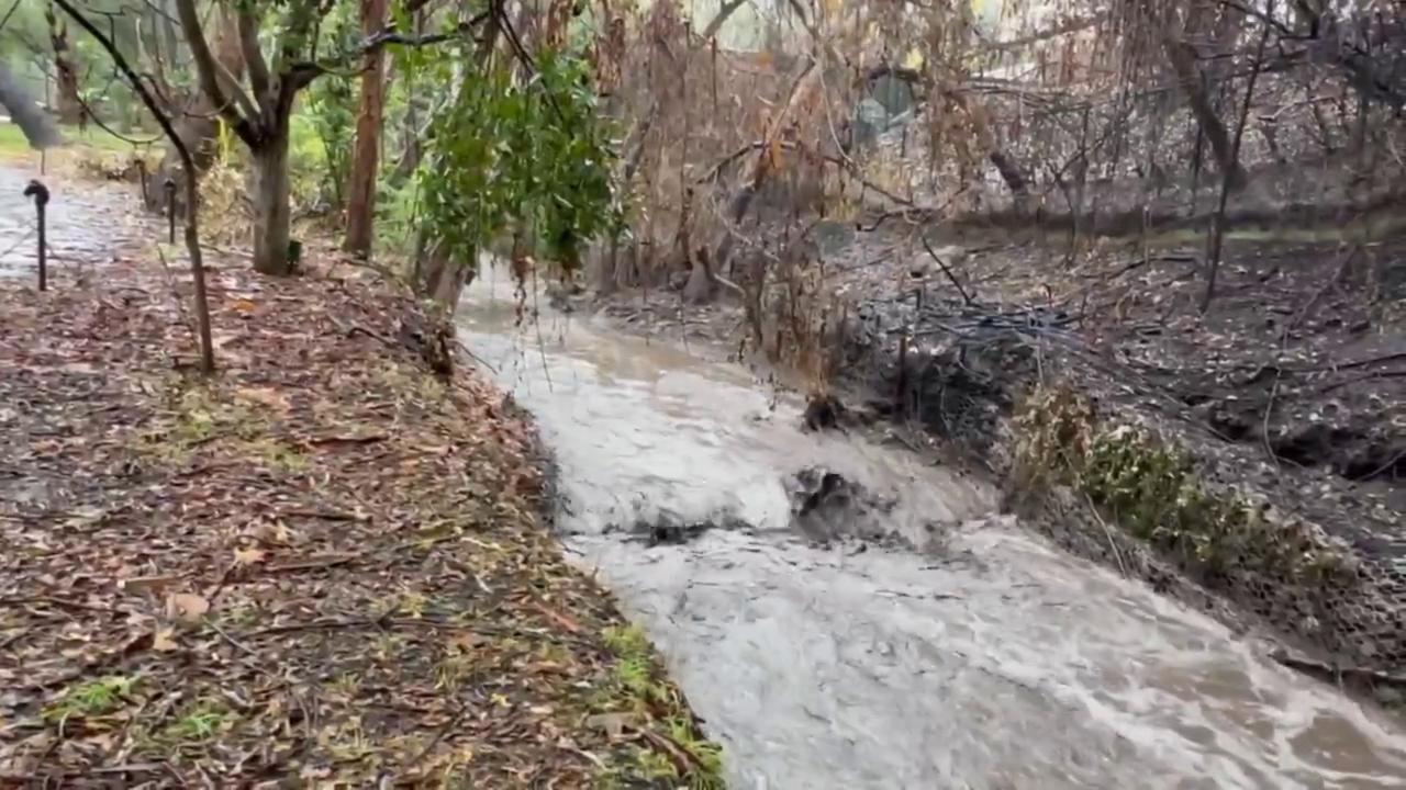 Rain run-off surges through Pacific Palisades, California