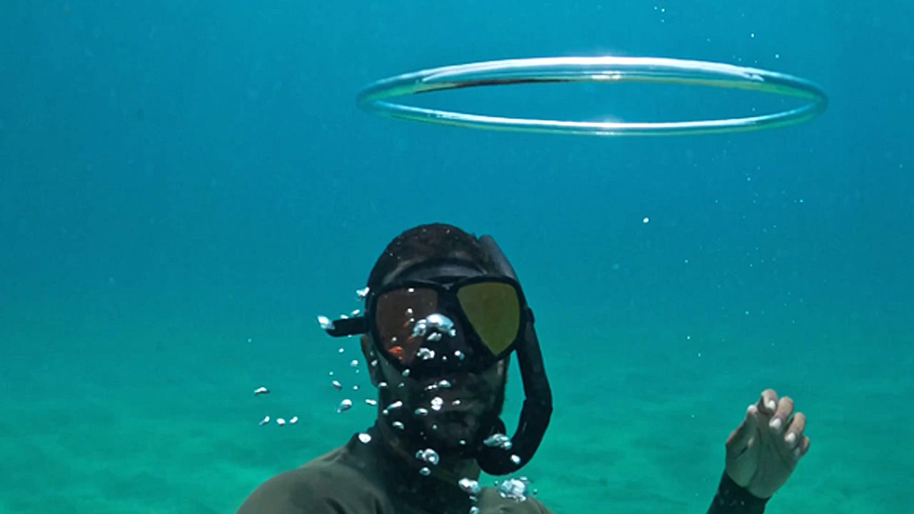 Snorkeler swims through bubble ring