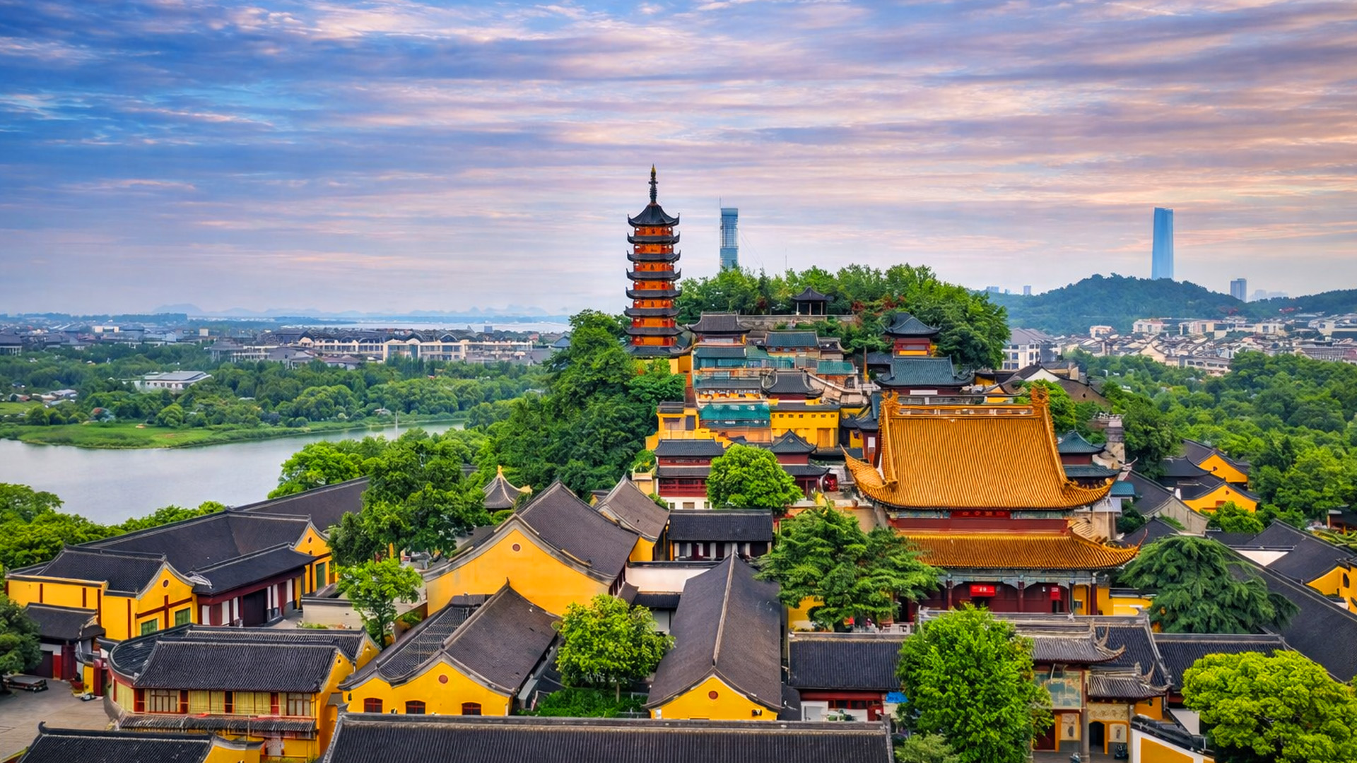 A traditional Chinese temple standing between nature and a modern city