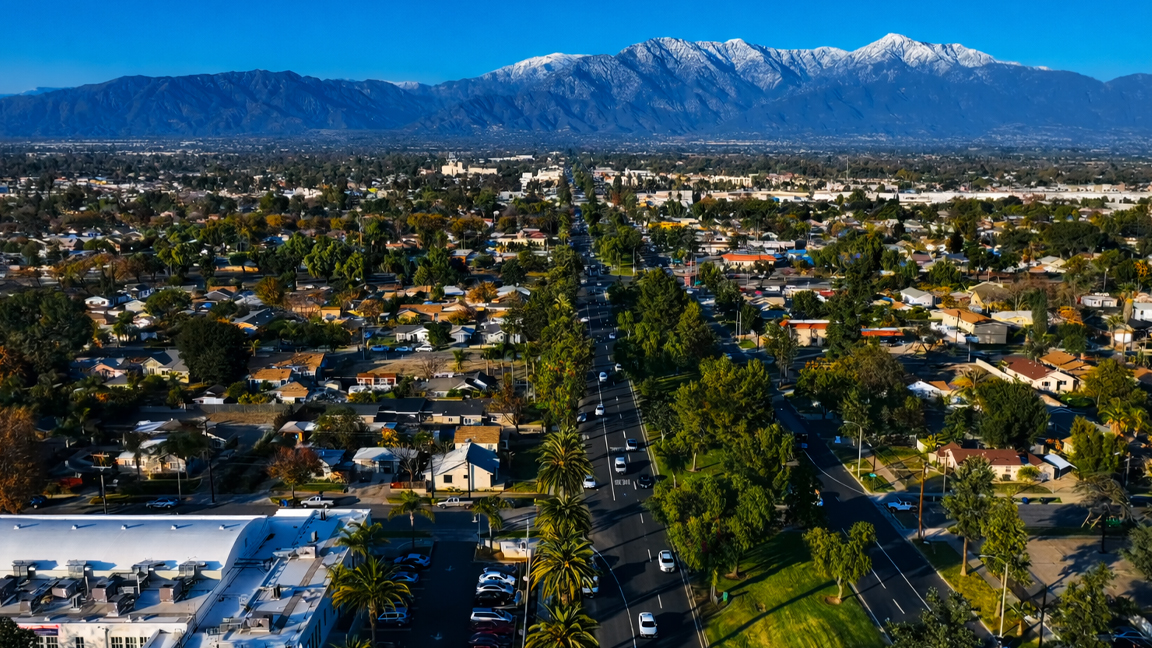 Urban neighborhood surrounded by trees with clear mountain backdrop