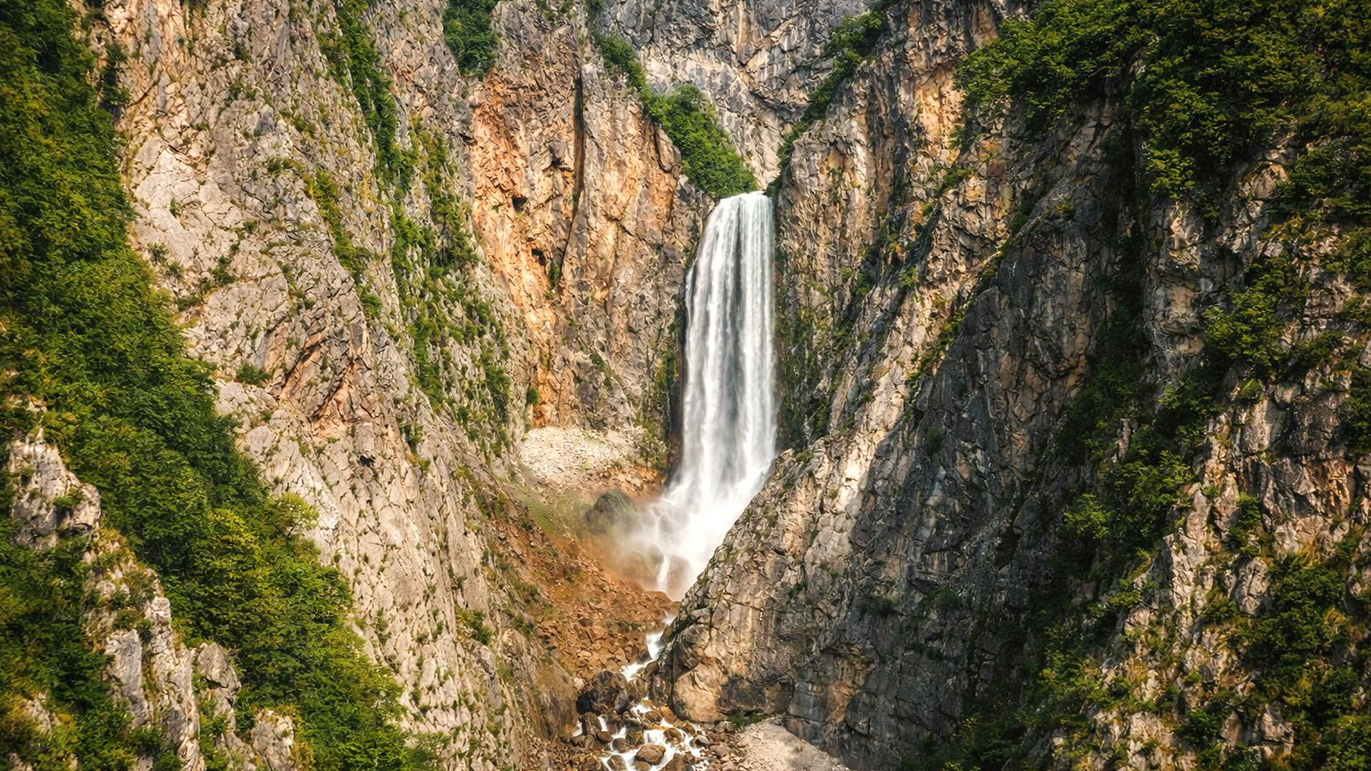 Uma imensa cachoeira despencando de um penhasco íngreme na montanha