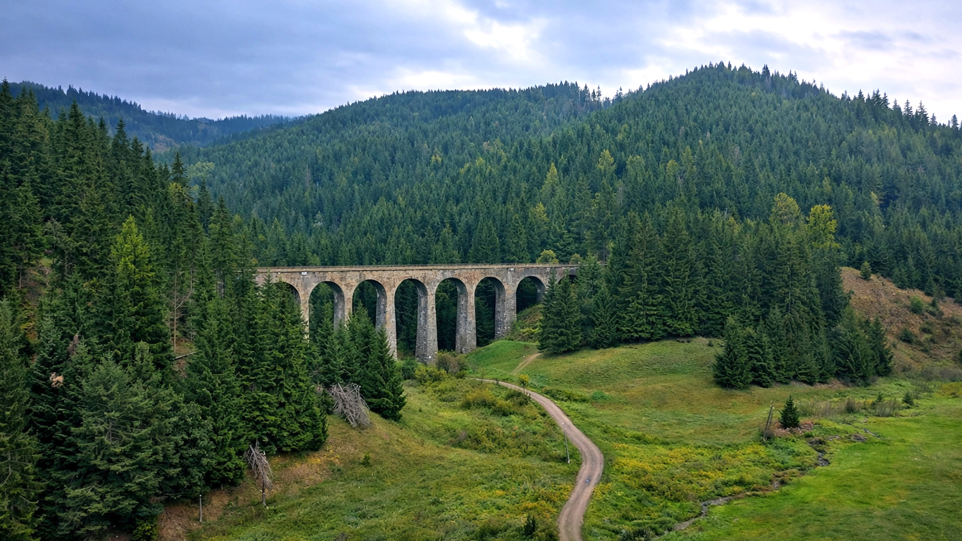 A long stone viaduct cutting through a remote mountain landscape