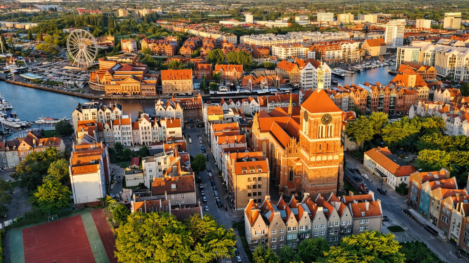 A river city with red roofs and warm evening light