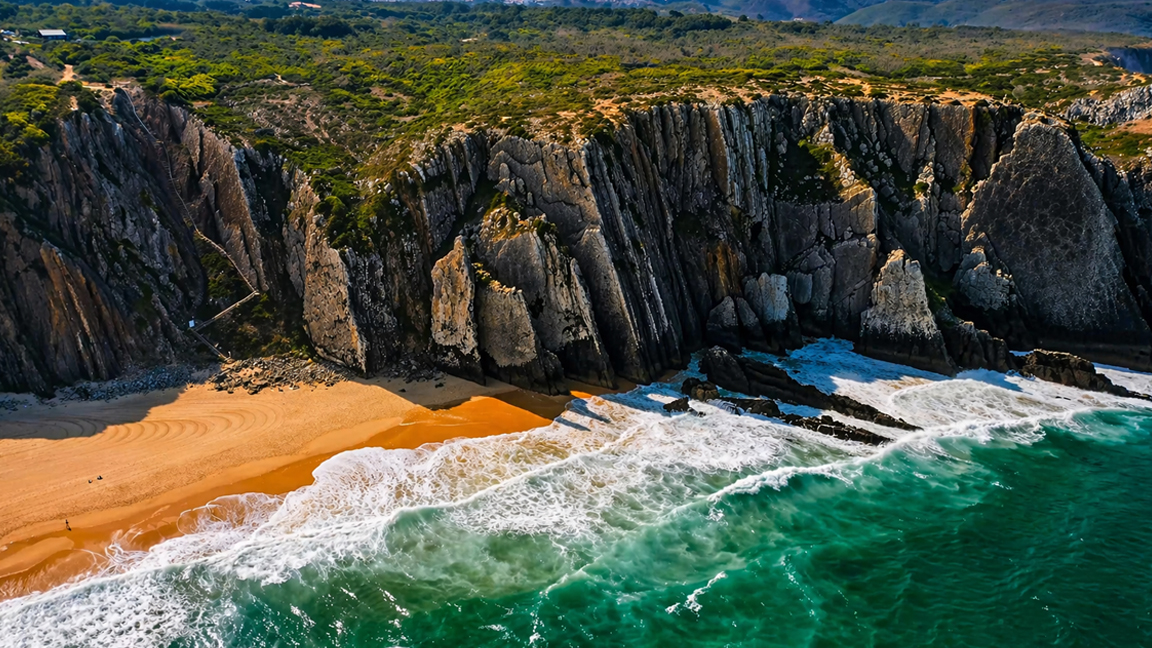 Golden sand beach surrounded by towering ocean cliffs
