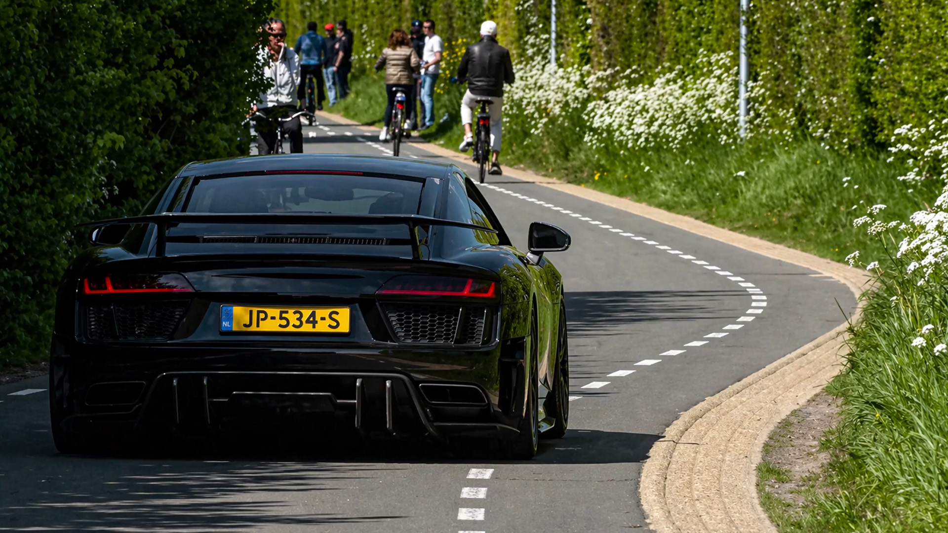 Audi R8 hard acceleration past cyclists on narrow road