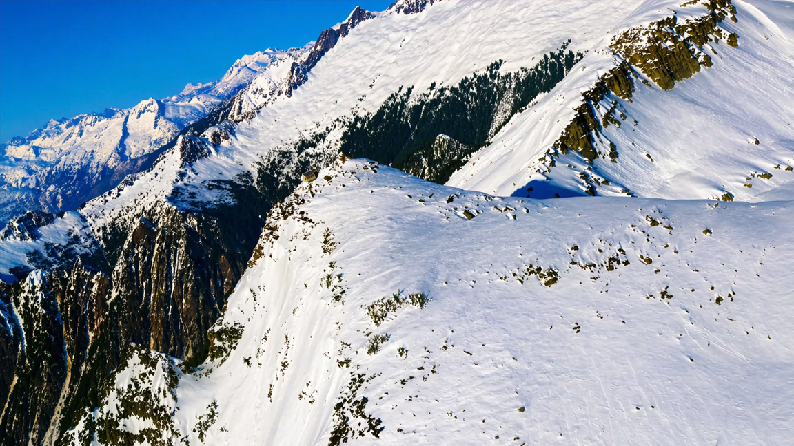 Vista aérea de montañas escarpadas nevadas con buen tiempo