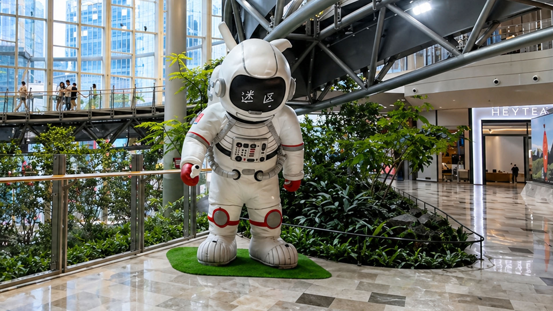 A giant astronaut stands in a mall filled with plants