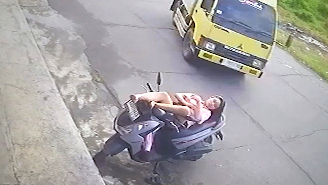 Woman narrowly avoids truck while resting on motorcycle in Indonesia