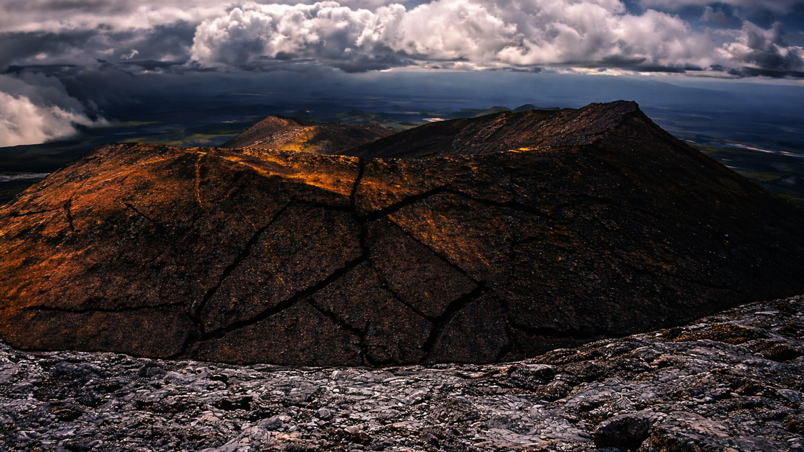 Dark volcanic terrain with cracked patterns and cloudy horizon